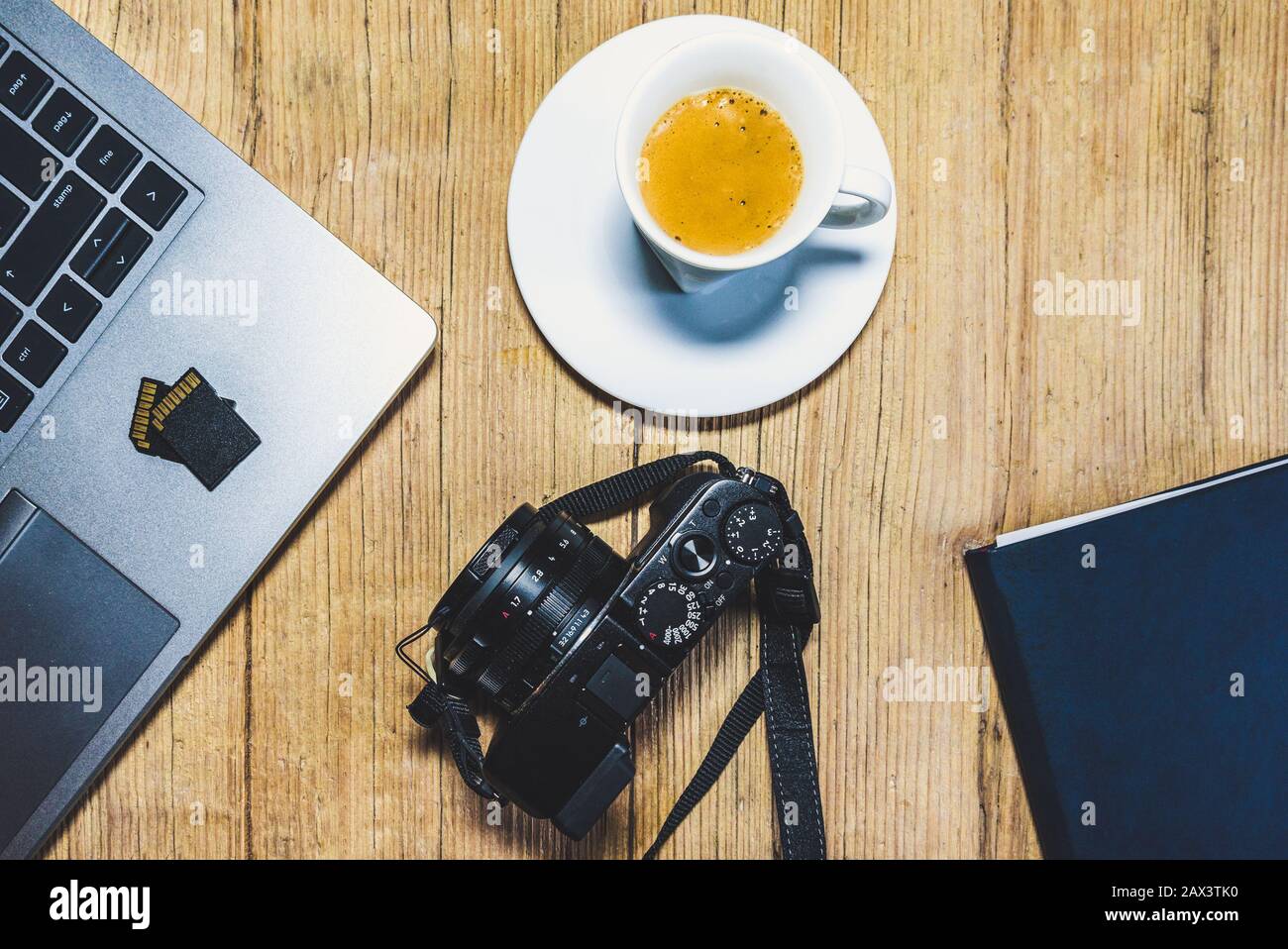 Wooden desk table with camera, laptop, memory cards, espresso cup and ...