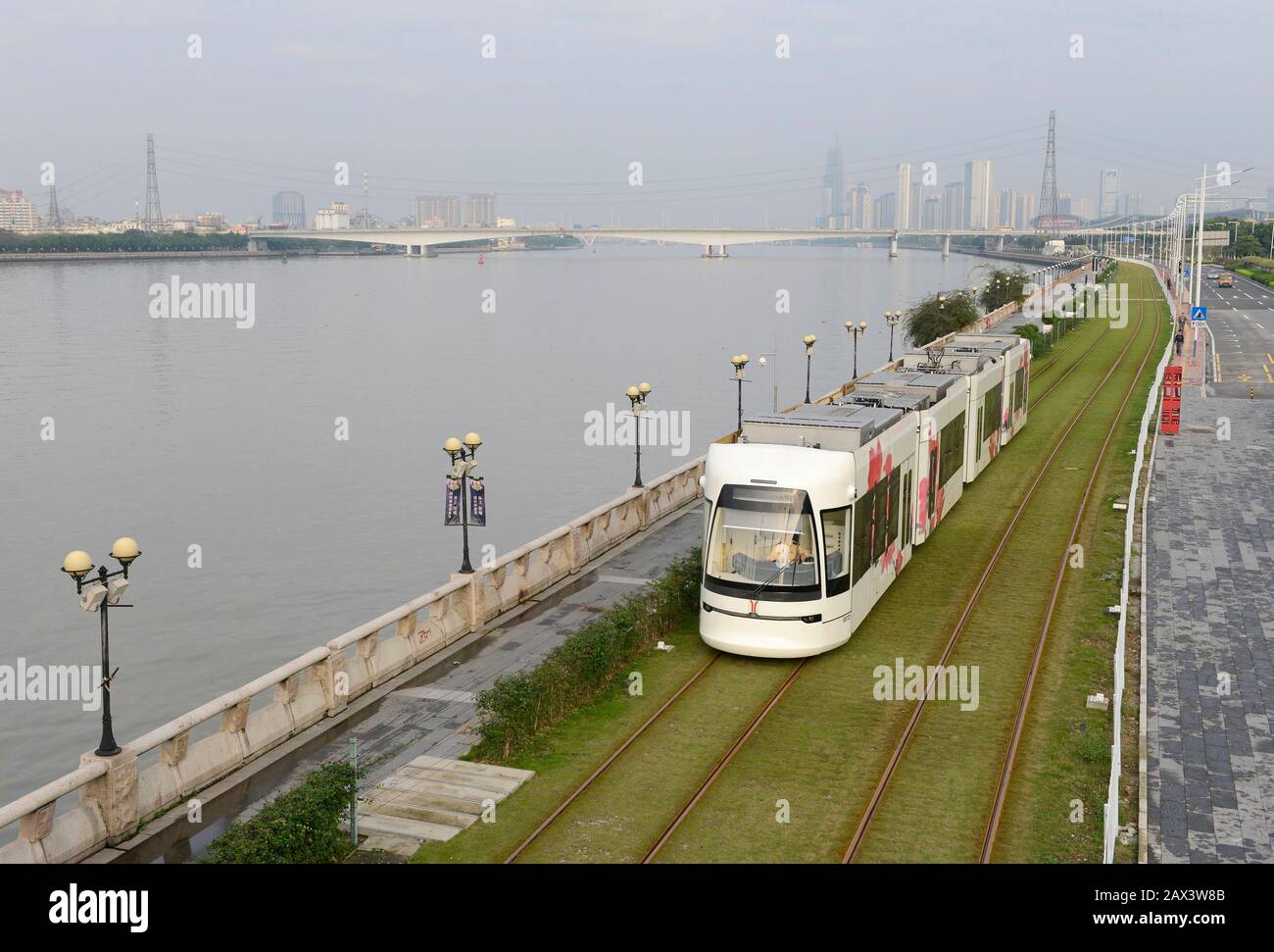 A tram travels by the Pearl river on the Haizhu tram system in ...