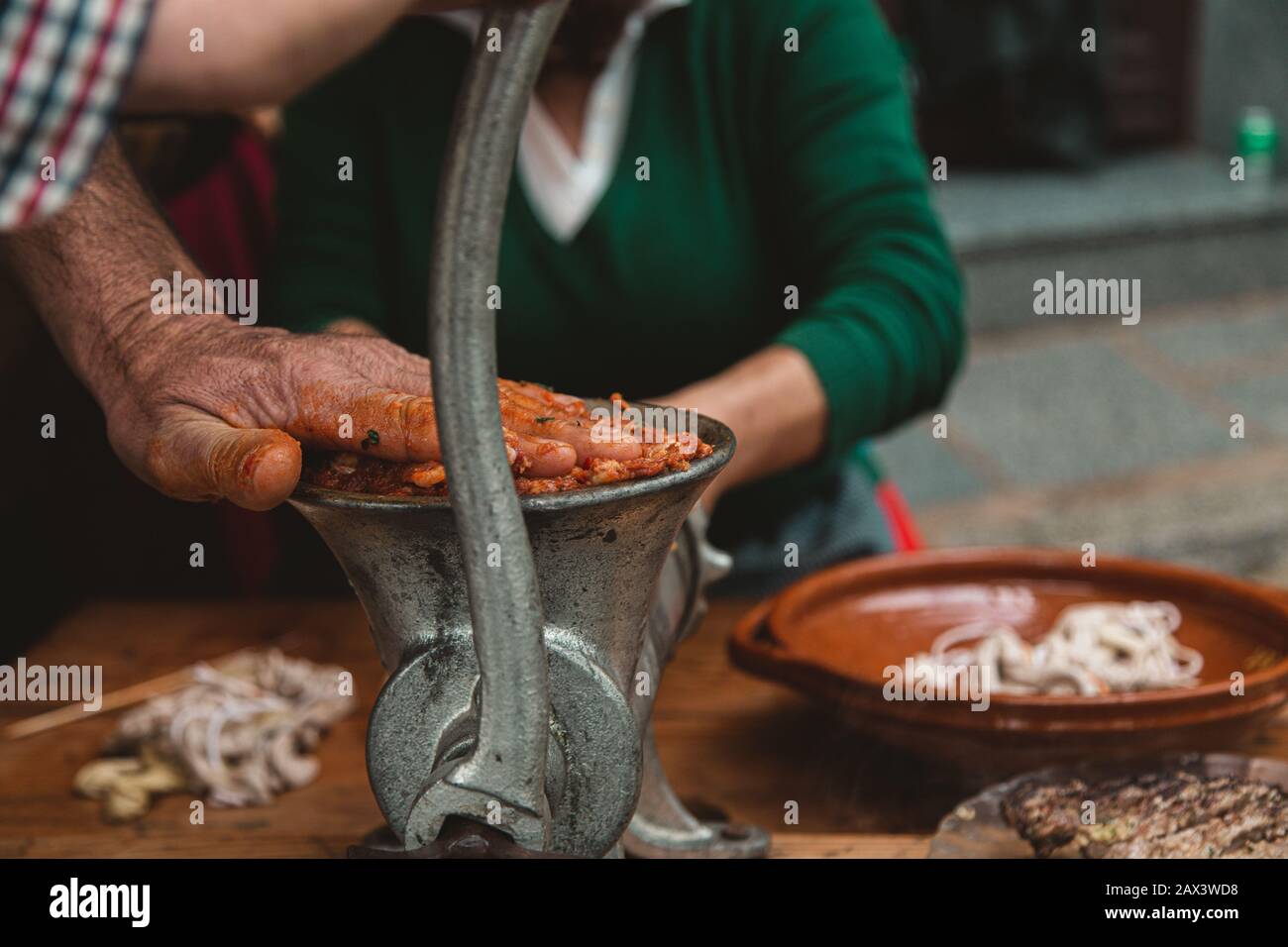 Man grinding meat with an old fashioned grinder on a wooden table with ...