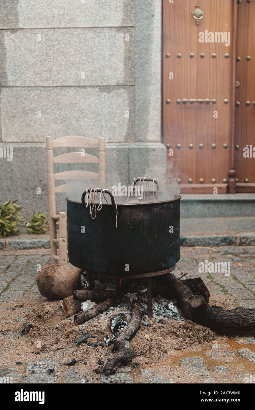 Metallic pot with boiling water on the fire surrounded by buildings ...