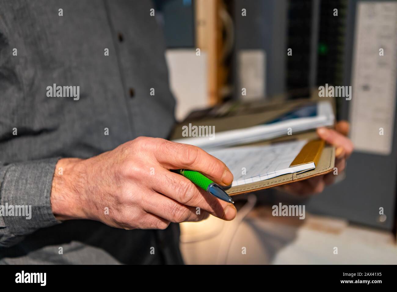 inspector holding a notebook in his hand next to an electric circuit ...