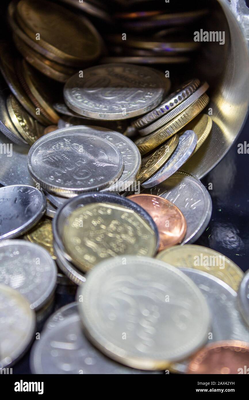 worn-out edges of old coins falling out of a tin cup Stock Photo - Alamy