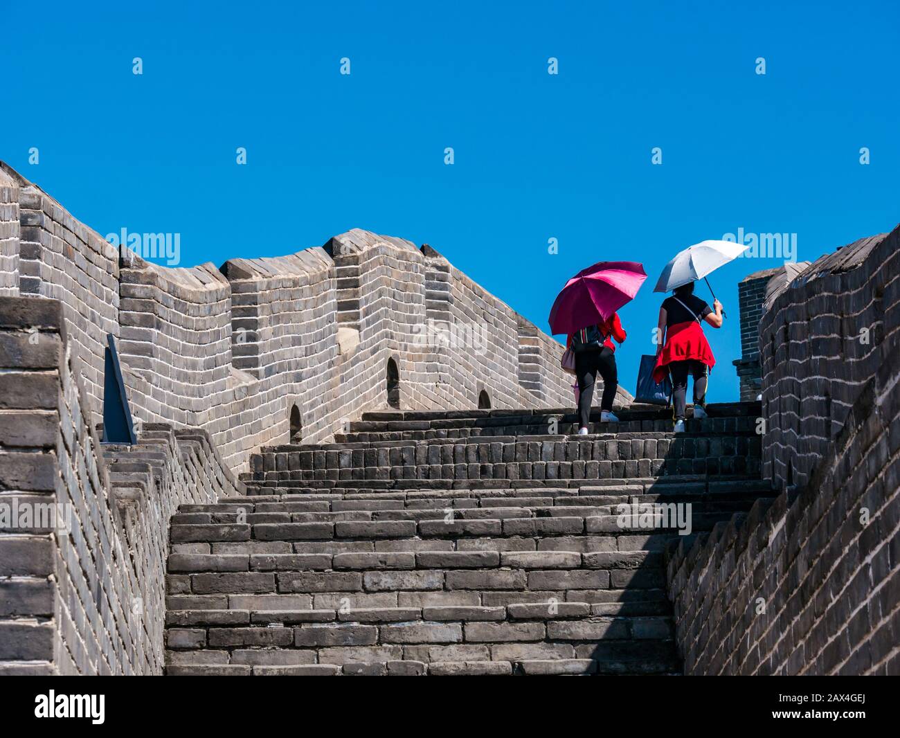 Chinese women holding sunshade parasols walking up steps at Jinshanling ...