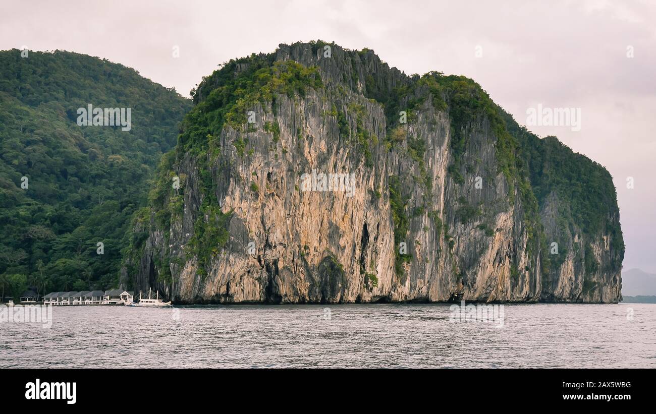 Massive limestone outcrop dwarfs beach cabanas - El Nido, Palawan ...