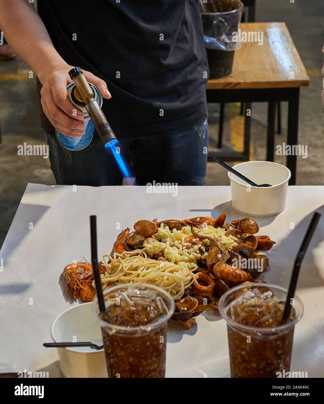 Chef is preparing street food with a bunsen burner directly at the ...