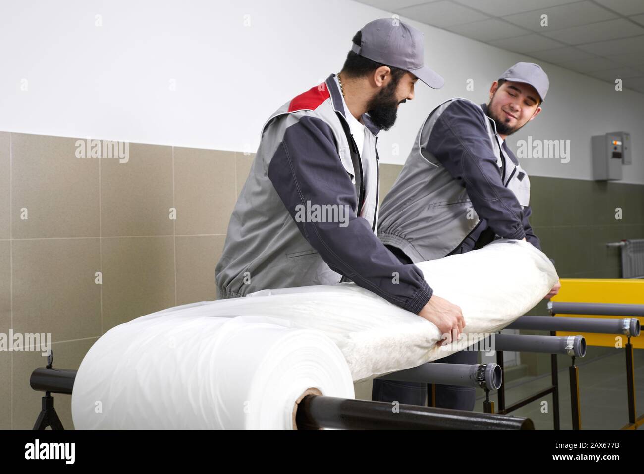 Men workers packing carpet in a plastic bag after cleaning it in ...