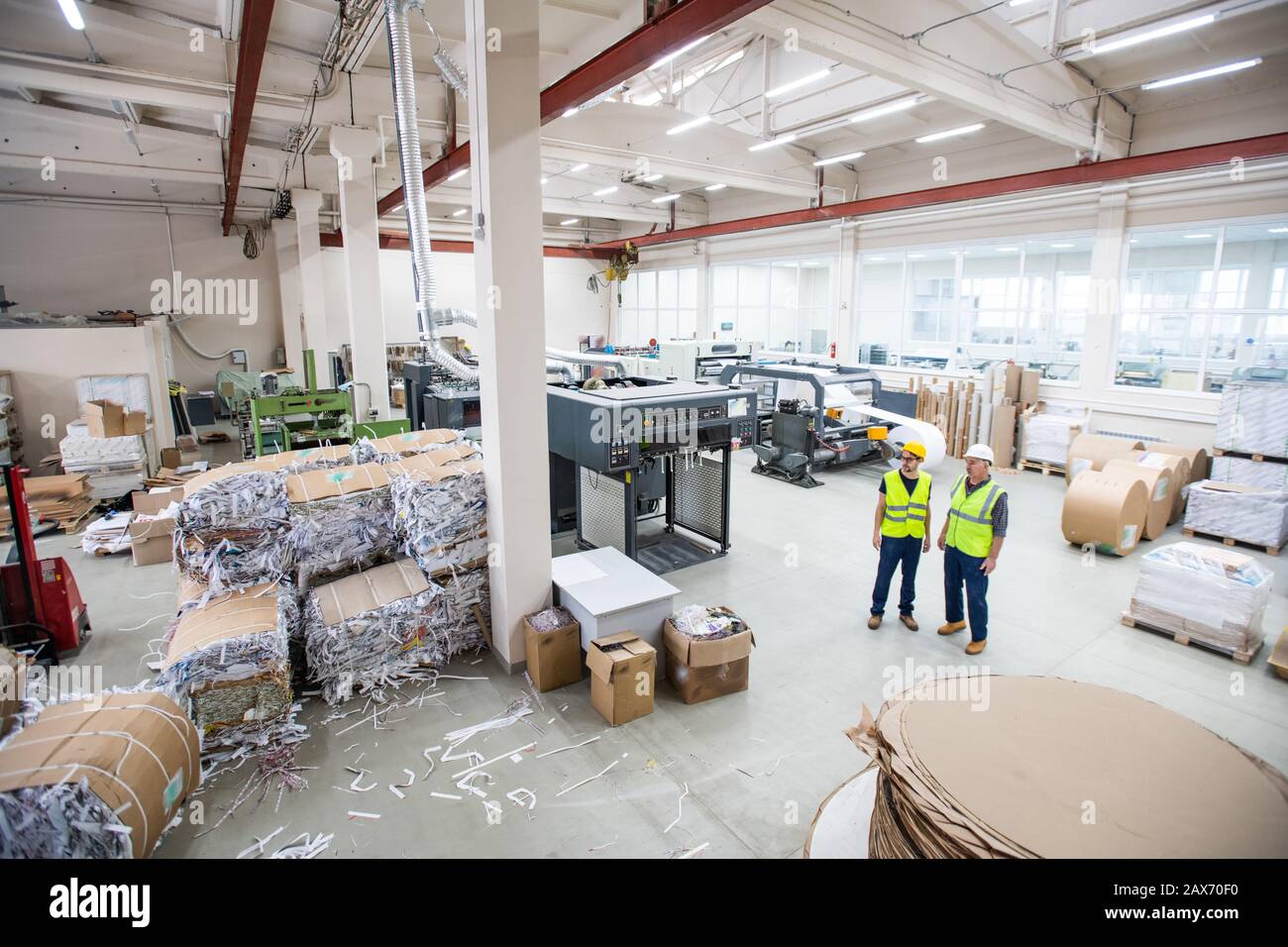 Workers of paper recycling factory wearing reflective vests standing in ...