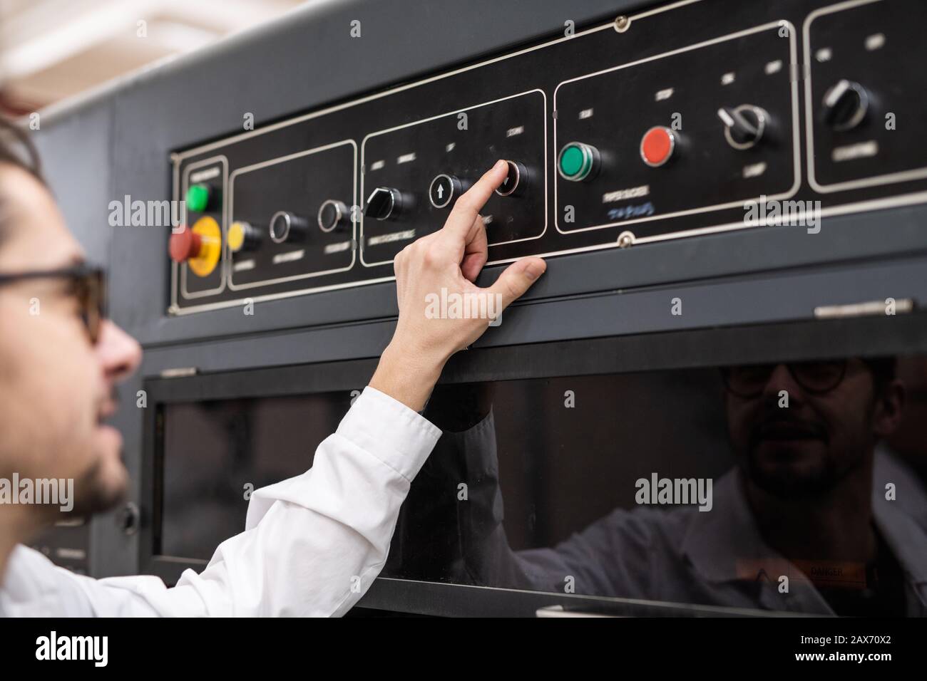 Over shoulder view of young operator pushing button on control panel ...