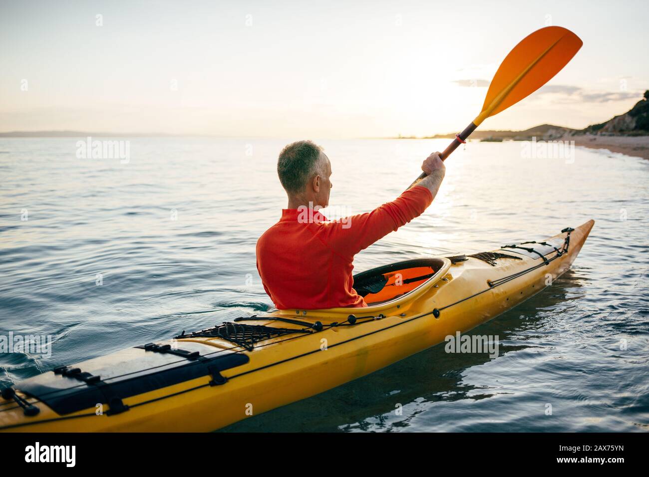 Rear view of older man enjoy kayaking on the sunset sea Stock Photo - Alamy