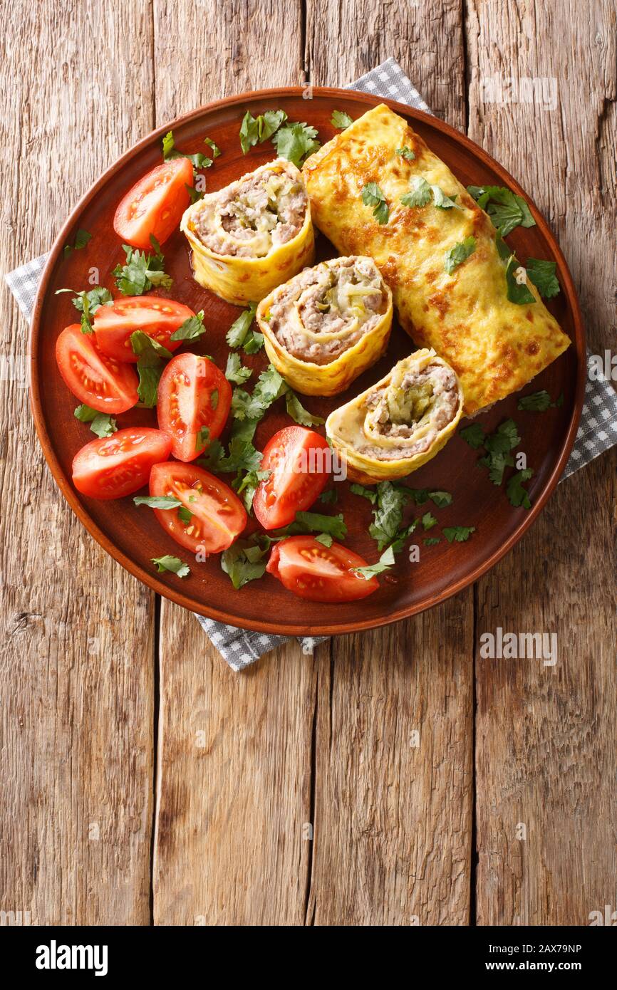 Brizol omelet stuffed with minced meat, cheese and pickles close-up in ...