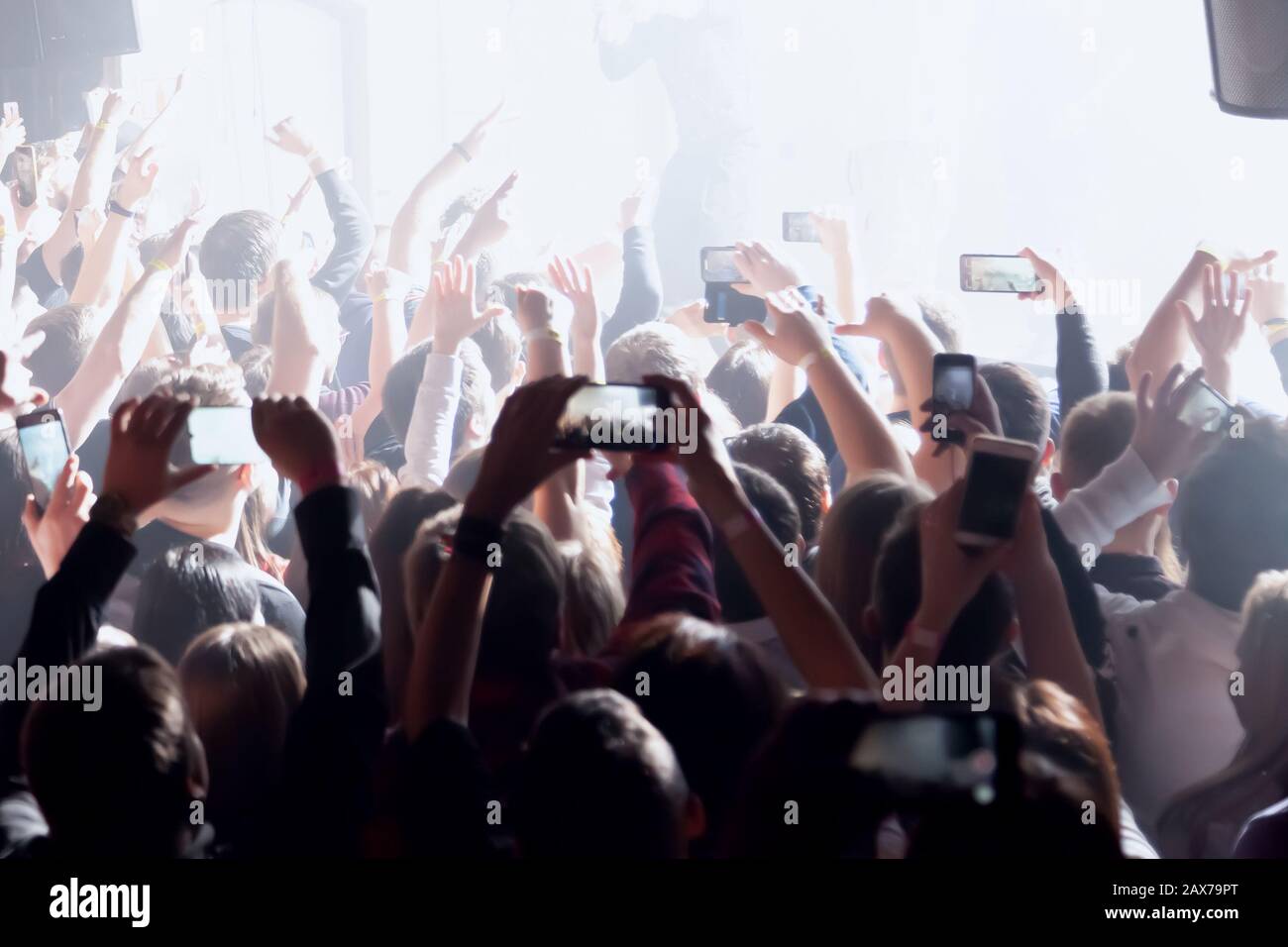 Audience with hands raised at a music festival with colored lights ...