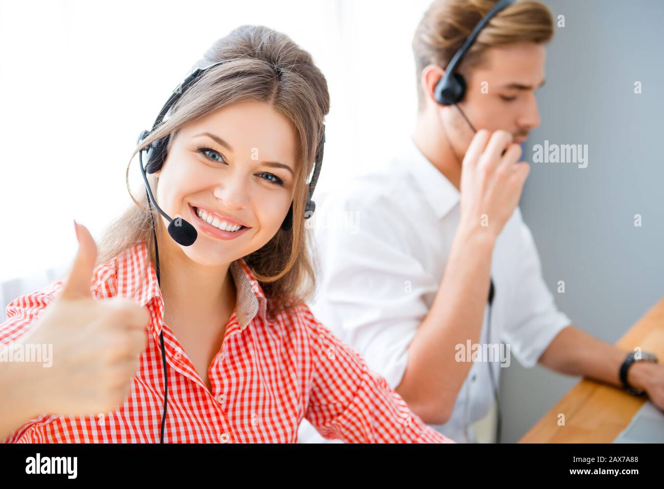 Young operator of call center showing thumb up Stock Photo - Alamy