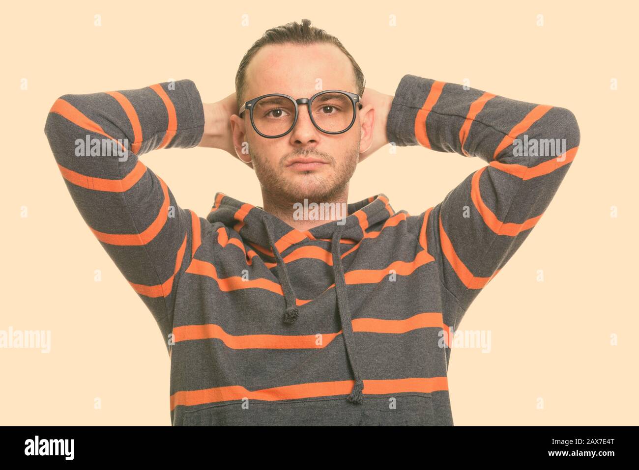 Studio shot of young man brushing hair back with both hands Stock Photo ...