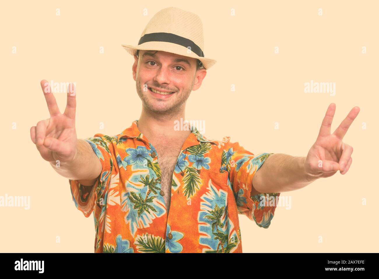 Studio shot of young happy man smiling while giving peace sign with ...