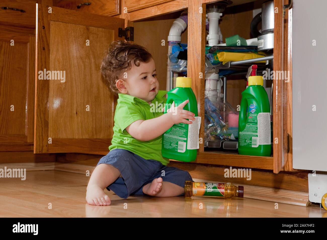 Child playing with dangerous chemical bottle in the kitchen Stock Photo ...