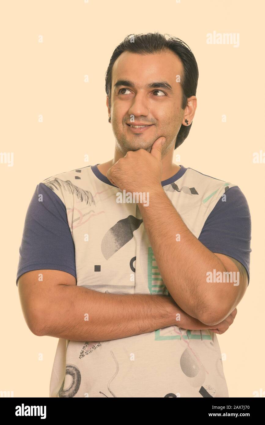 Studio shot of happy Persian man smiling and thinking while looking up ...