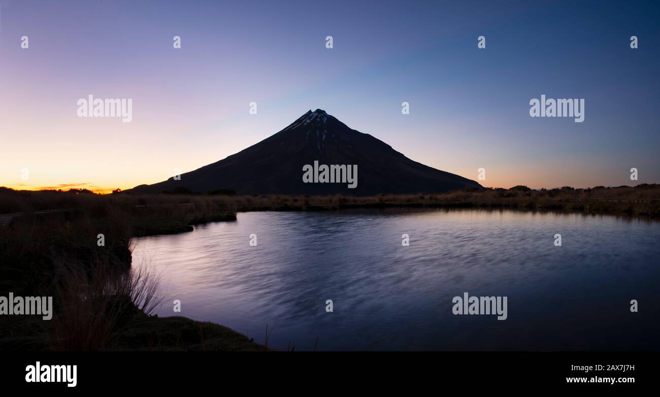 Majestic Mount Taranaki reflected in the clear water of Pouakai tarn at ...