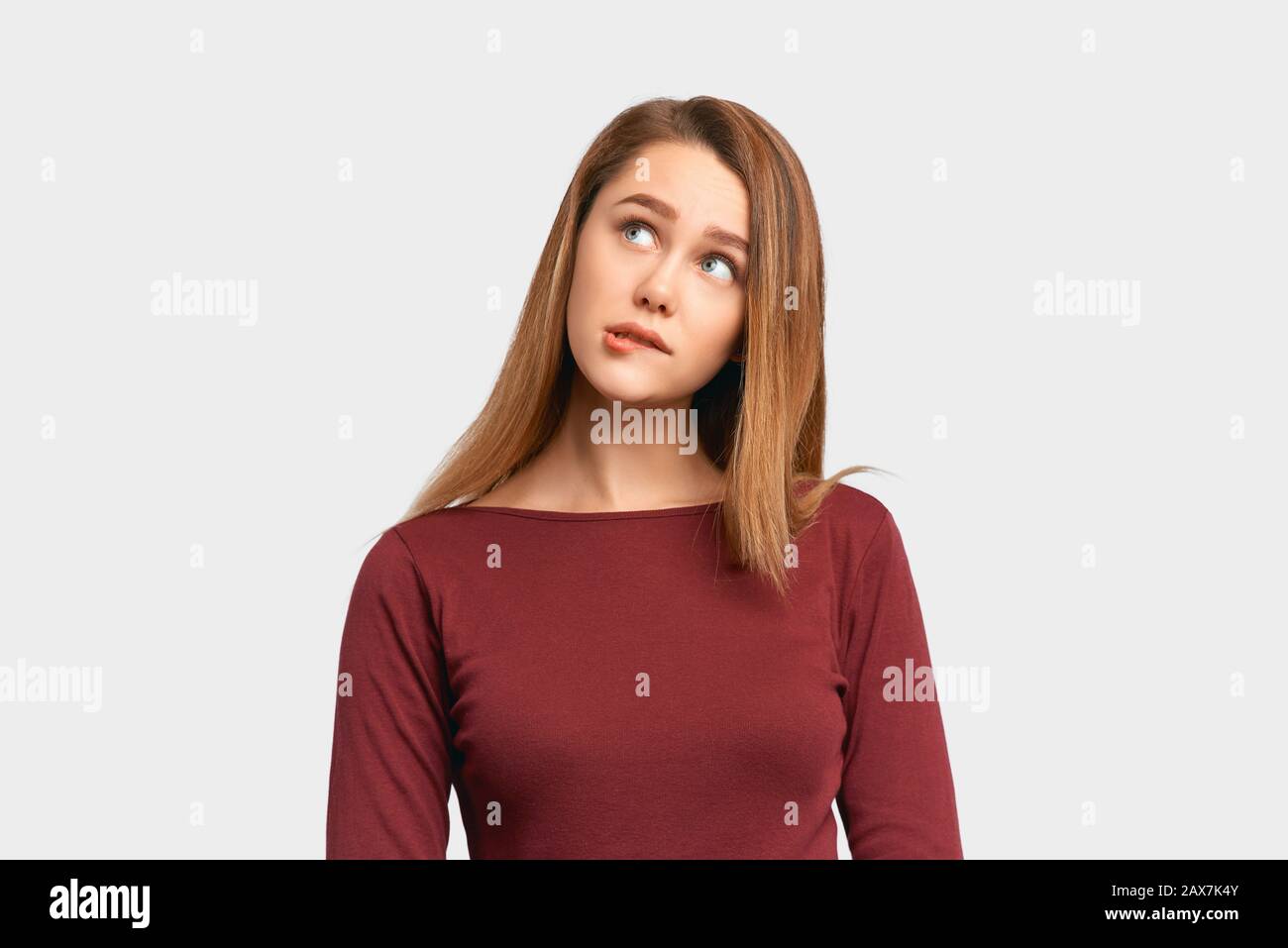 Puzzled woman curving lips thinking something over Stock Photo - Alamy