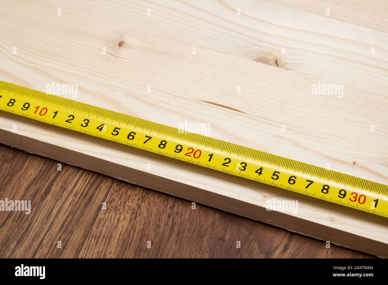 Measuring a wooden board with an yellow tape measure close up Stock ...