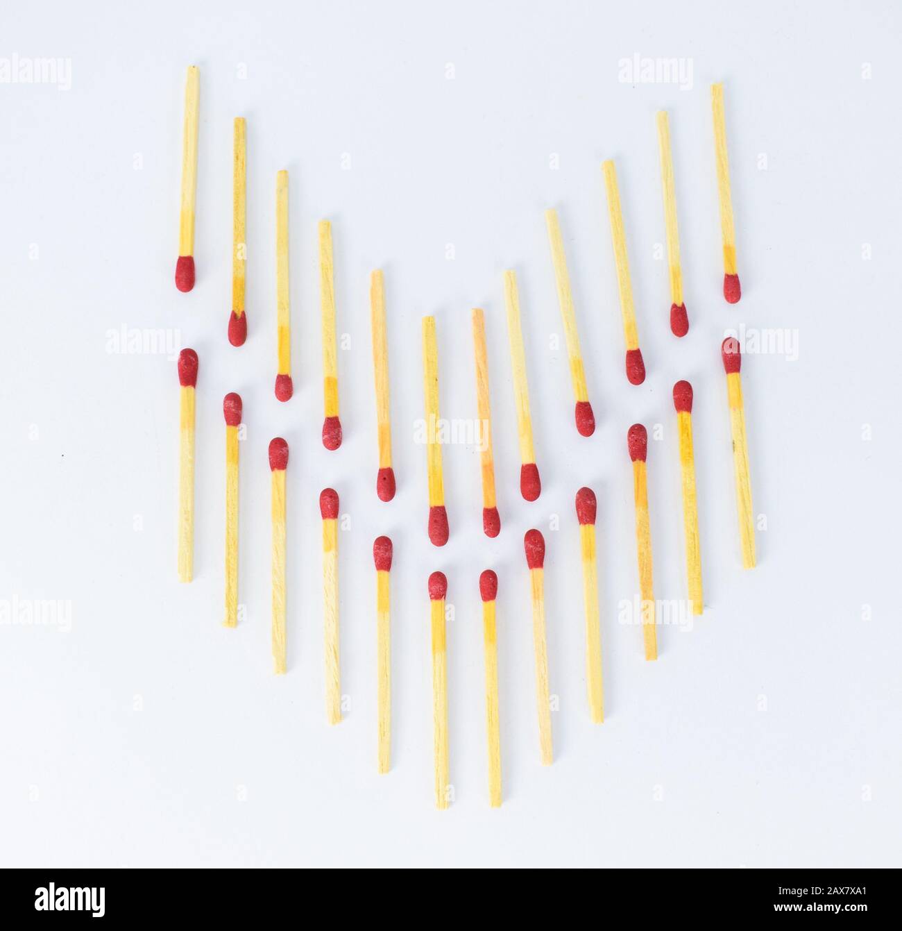 An arrow shape made of two rows of red match sticks on a white ...