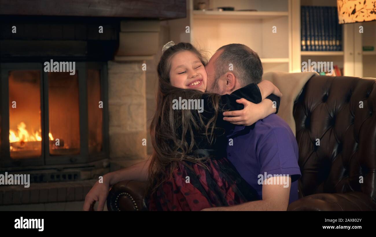 Happy Small Girl Hugging Her Daddy Tightly Sitting On His Knees In The