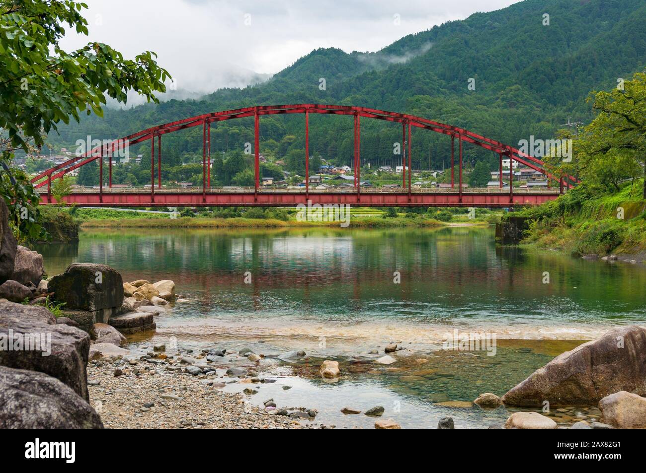 Japanese countryside landscape with bright red bridge over Kiso river. Kiso valley, Nagano ...