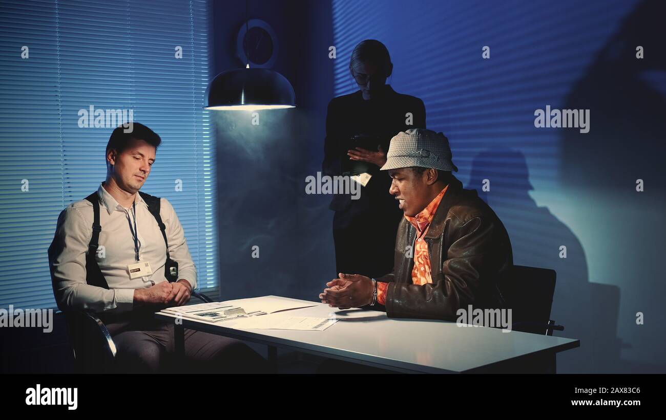 Medium shot of Police detective giving black murder criminal a document ...