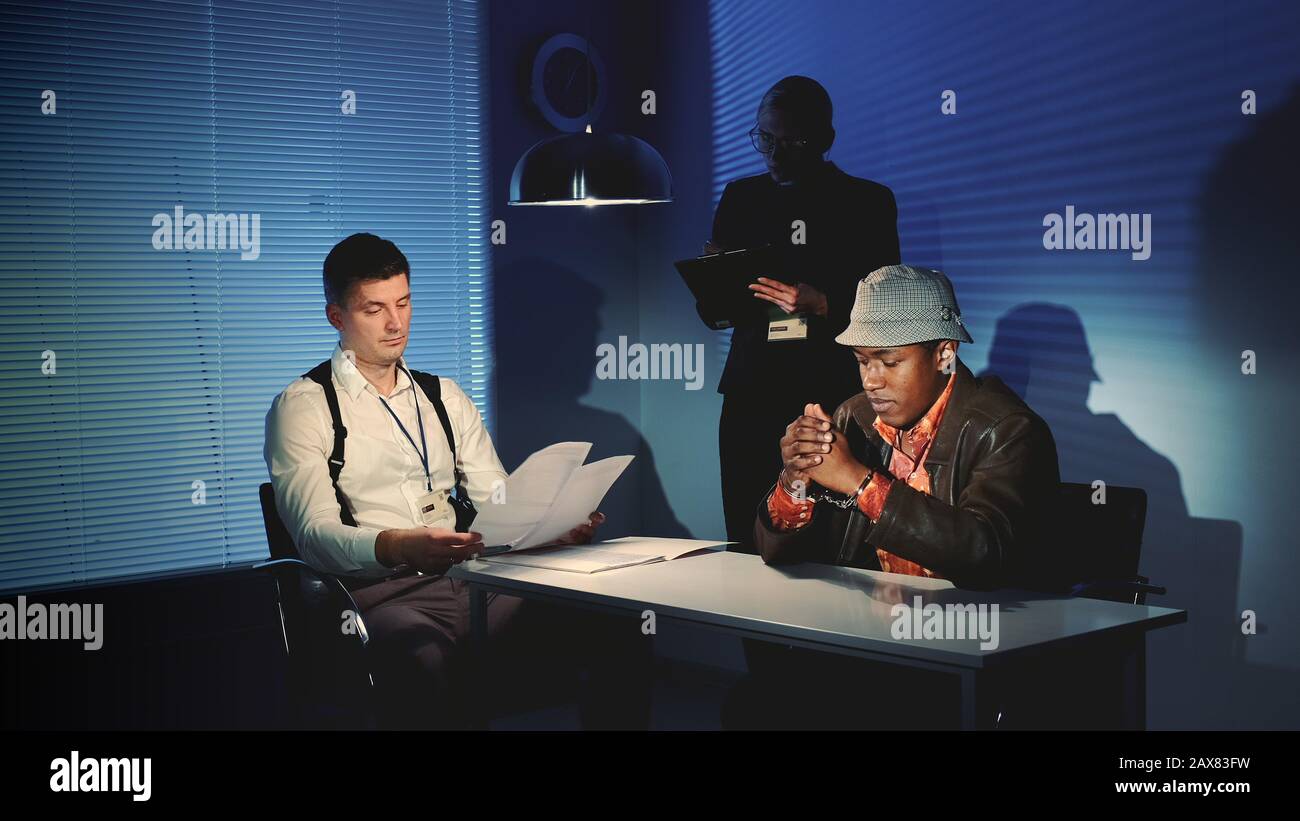 Police detective questioning suspect black man in interrogation room ...