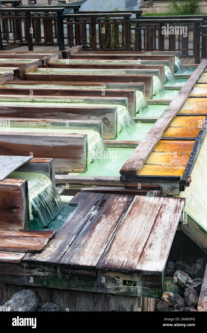 Mineral water flowing over wooden boxes of Yubatake onsen, hot spring ...