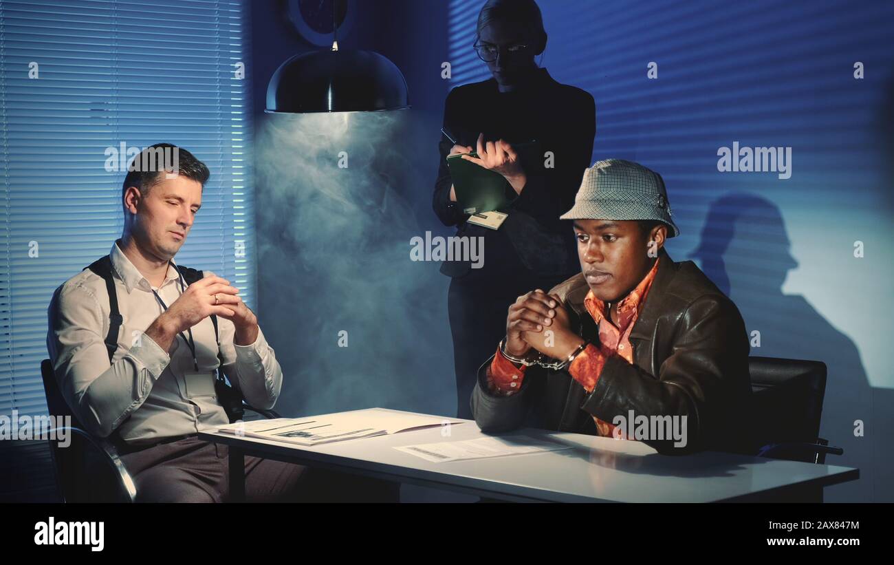 Medium shot of Black prisoner in handcuffs having interview with ...