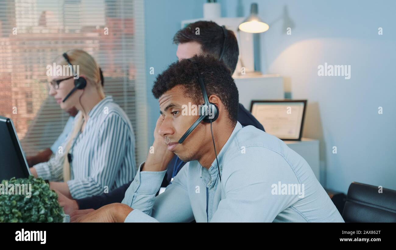 Bored multiethnic customer support operator waiting for telephone call ...