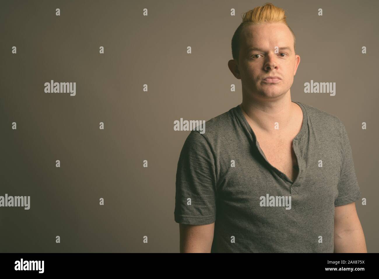 Man with Mohawk hairstyle and blond hair against gray background Stock ...