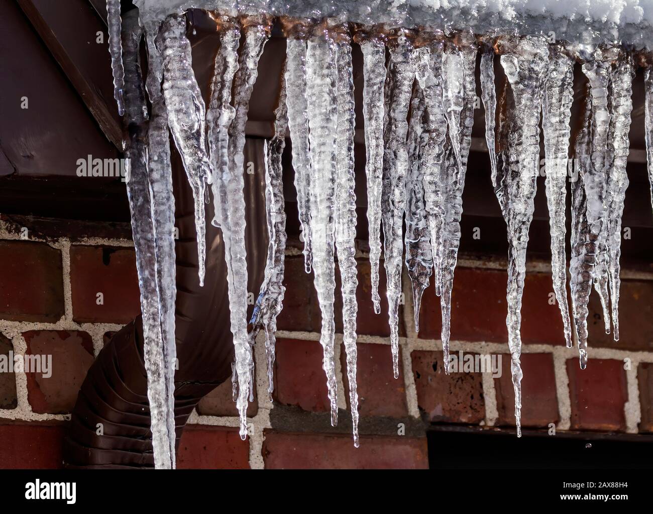 Ice icicles hanging from a roof gutter Stock Photo - Alamy