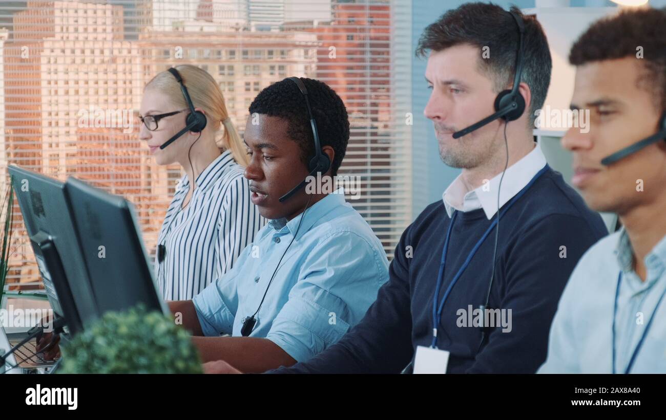 African customer service representative working on multiracial team of modern call center ...