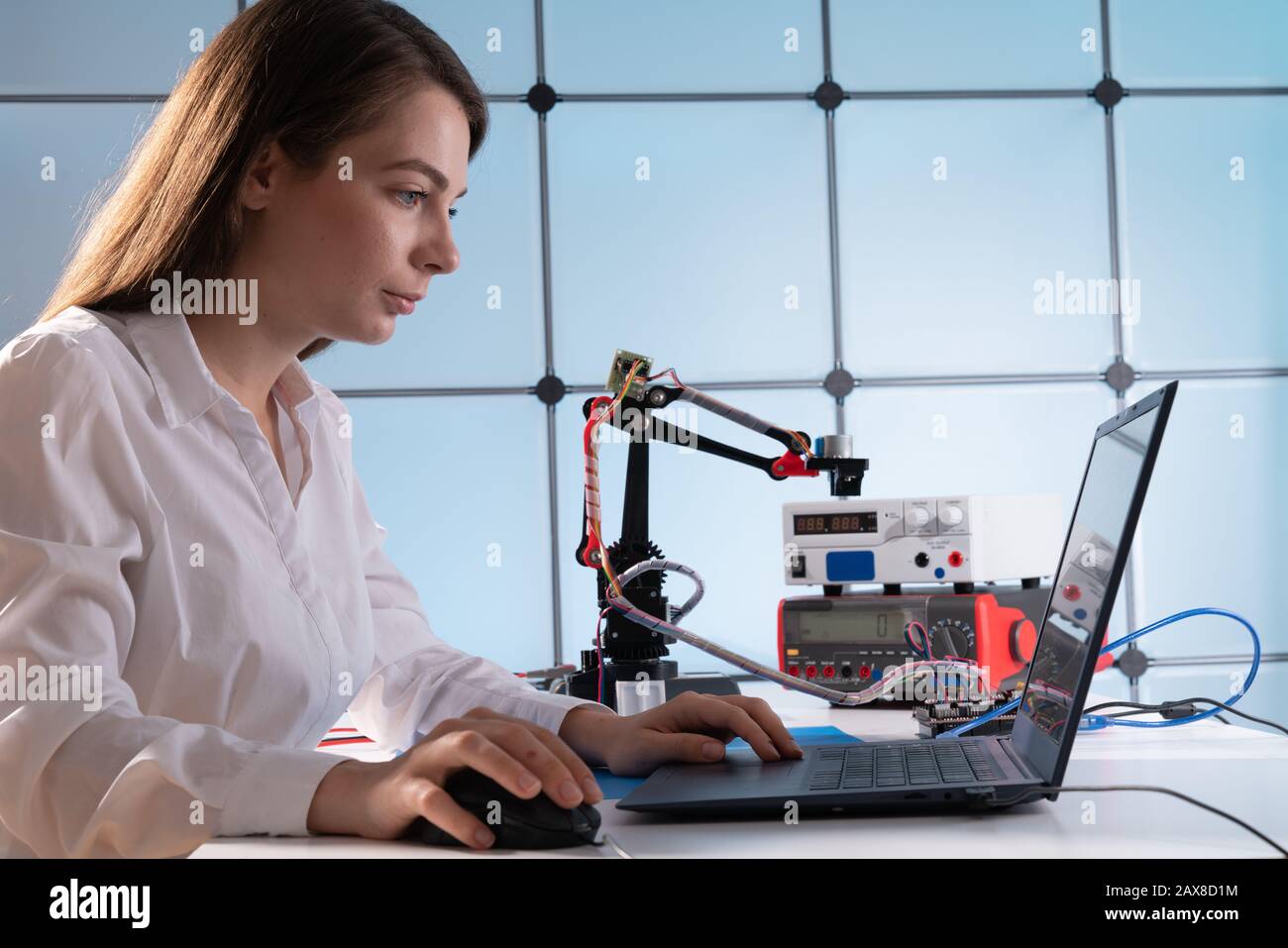 A young woman writes an algorithm for the robot arm. Science Research ...