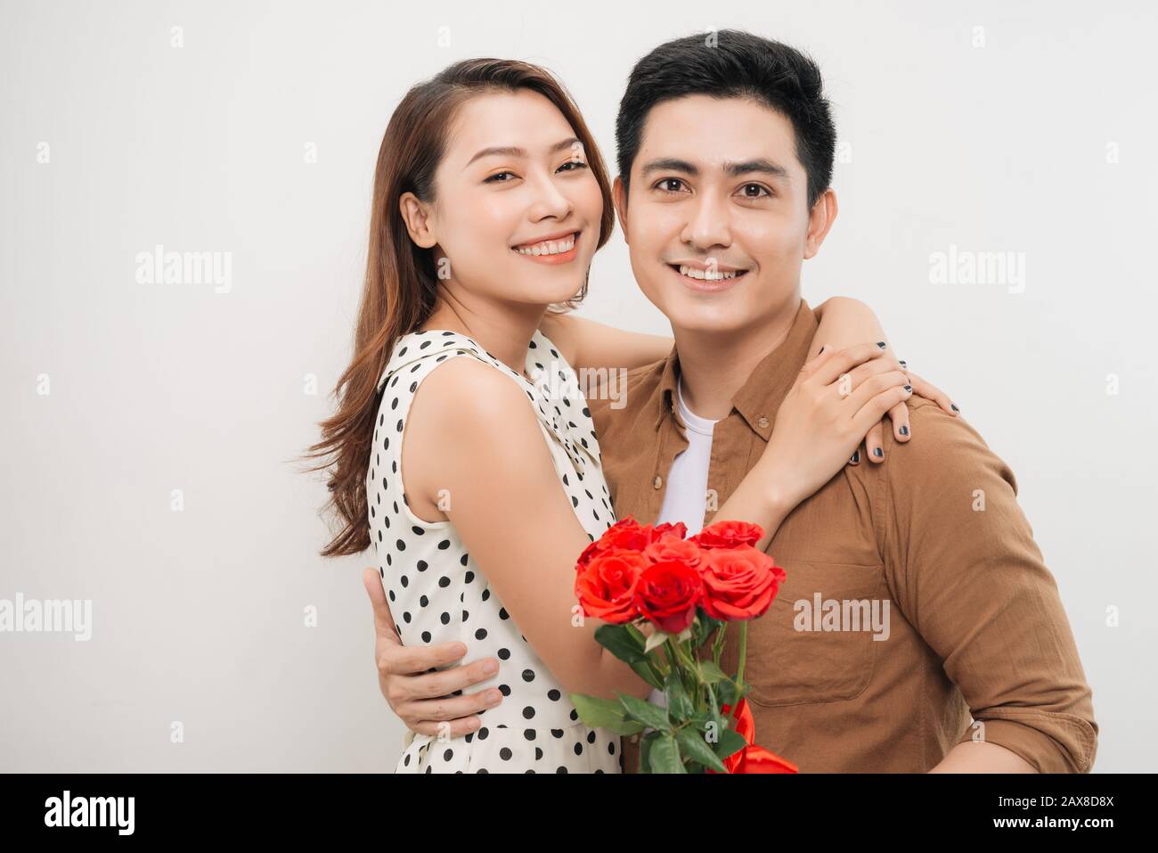 Beautiful young woman hugging her boyfriend and holding nice bouquet of ...