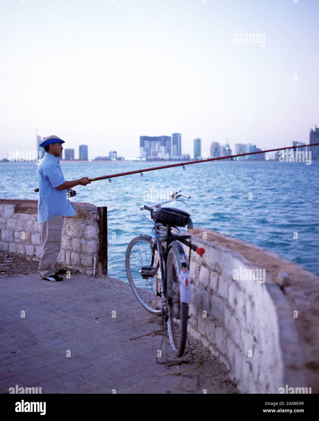 A man fishing, with the city in the background, Doha, Qatar Stock Photo ...