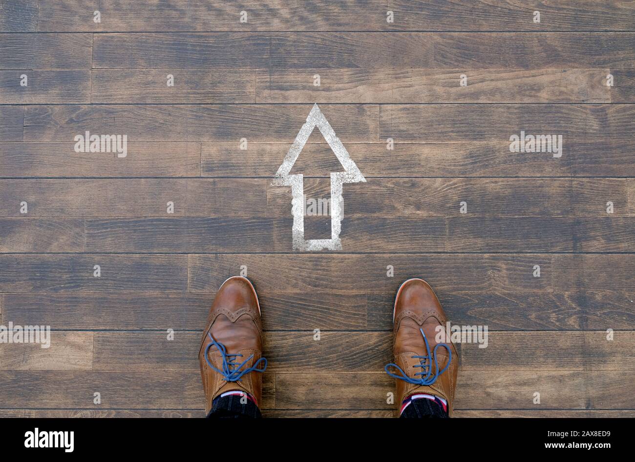 The way forward: Man standing in front of arrow sign on wooden floor ...