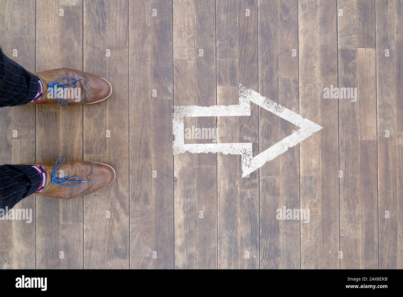 The way forward: Man standing in front of arrow sign on wooden floor ...