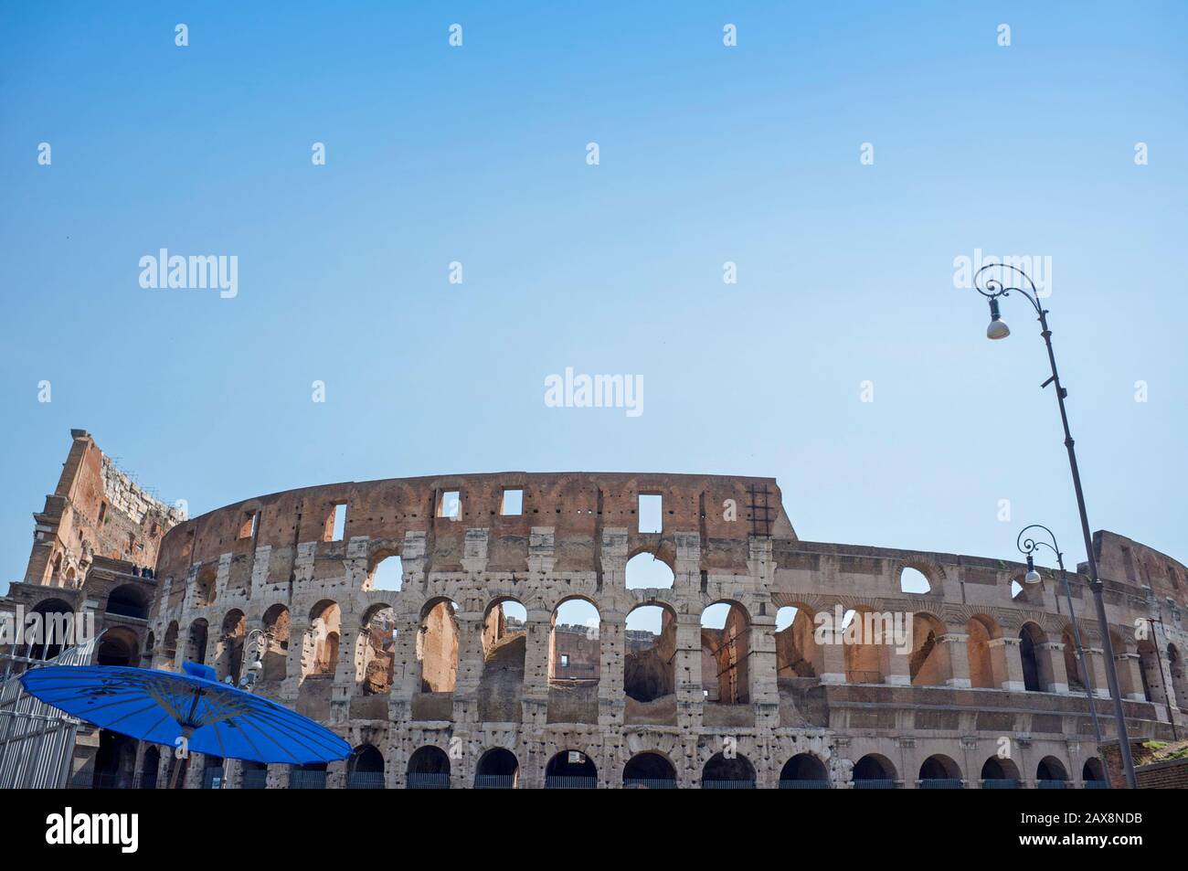external view of the colosseum of Rome with blue umbrella on the left ...