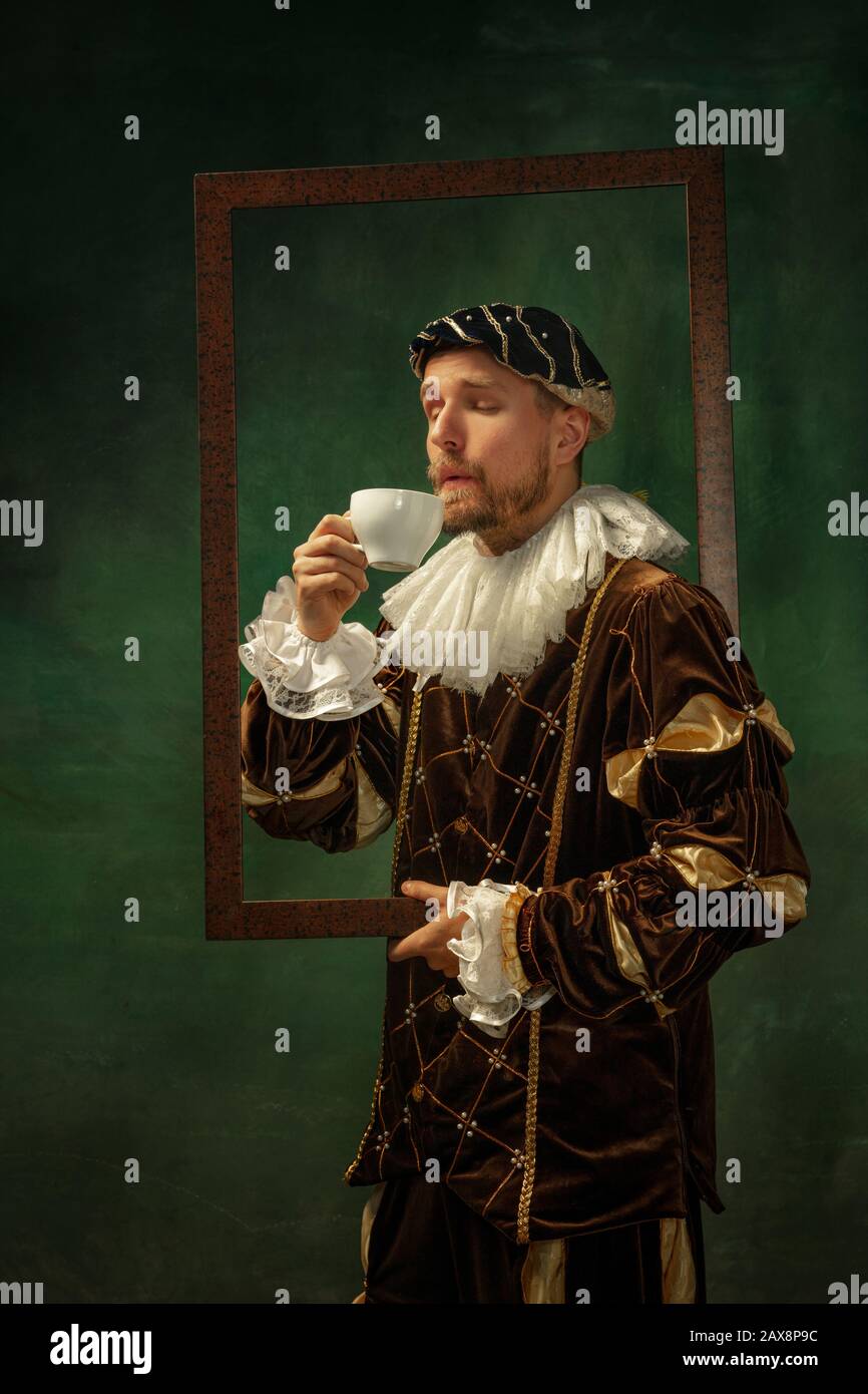 Enjoy aroma. Portrait of medieval young man in vintage clothing with ...