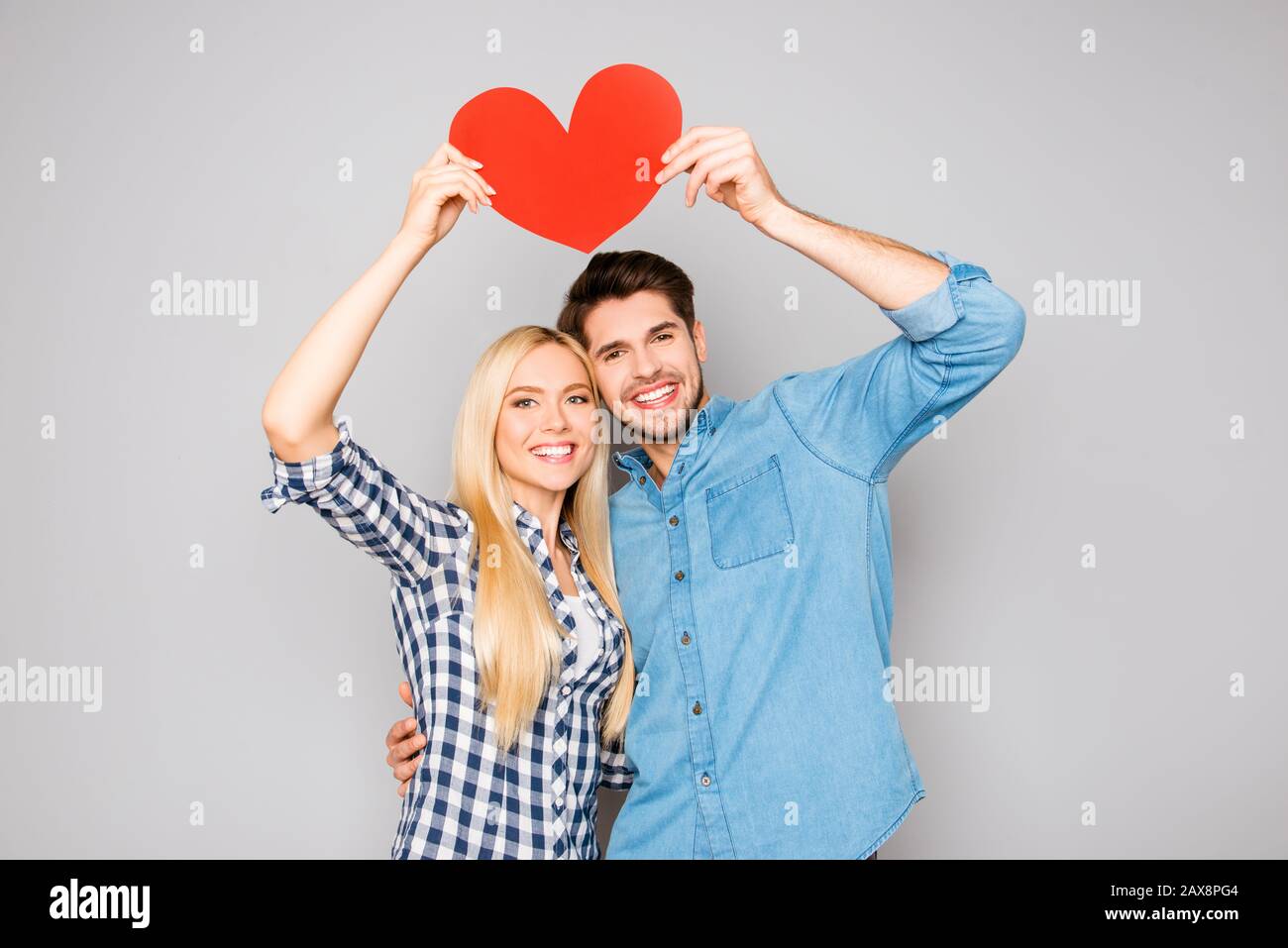 Portrait of two happy people holding red paper heart under head Stock ...