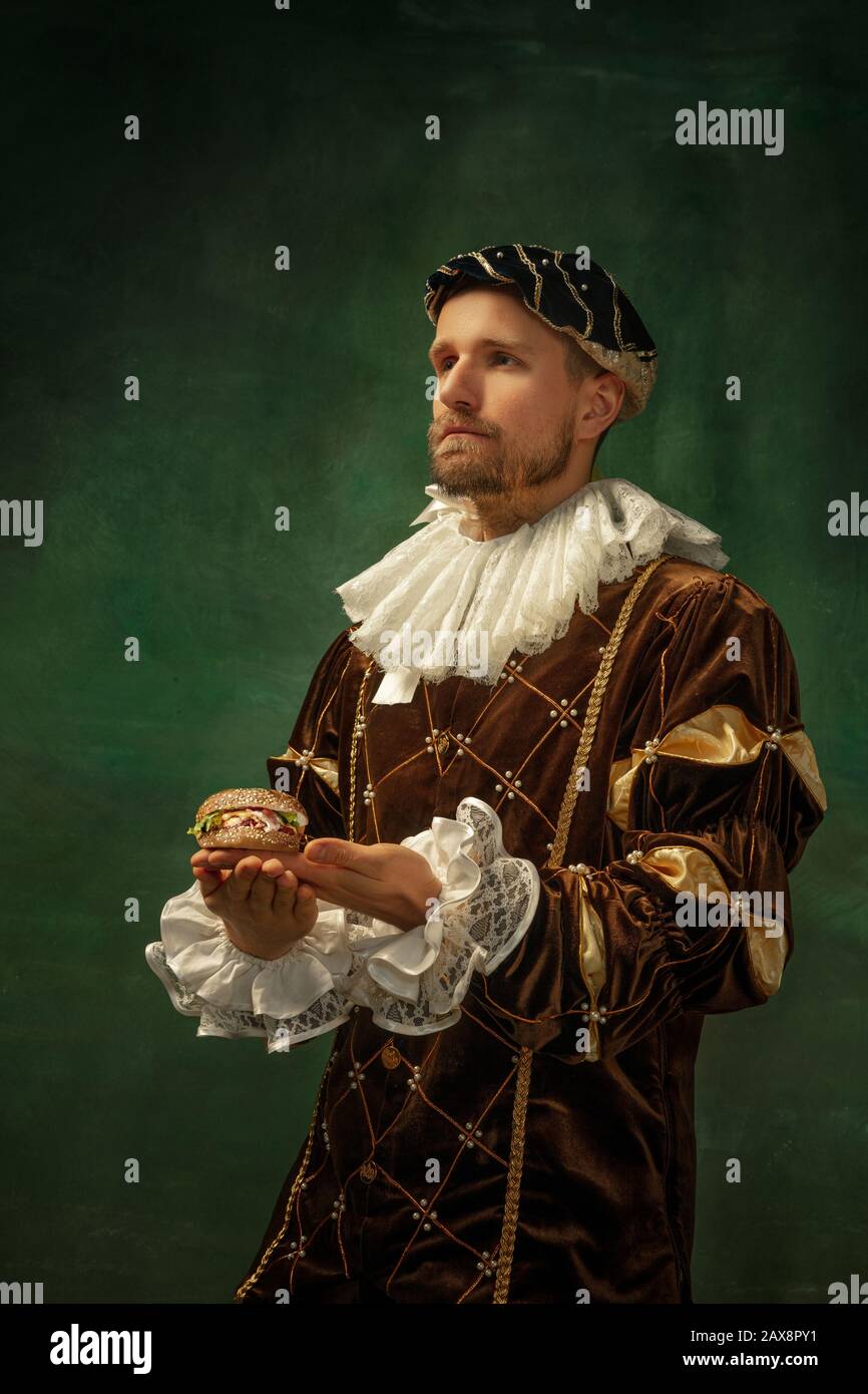 Fast food joyful. Portrait of medieval young man in vintage clothing ...
