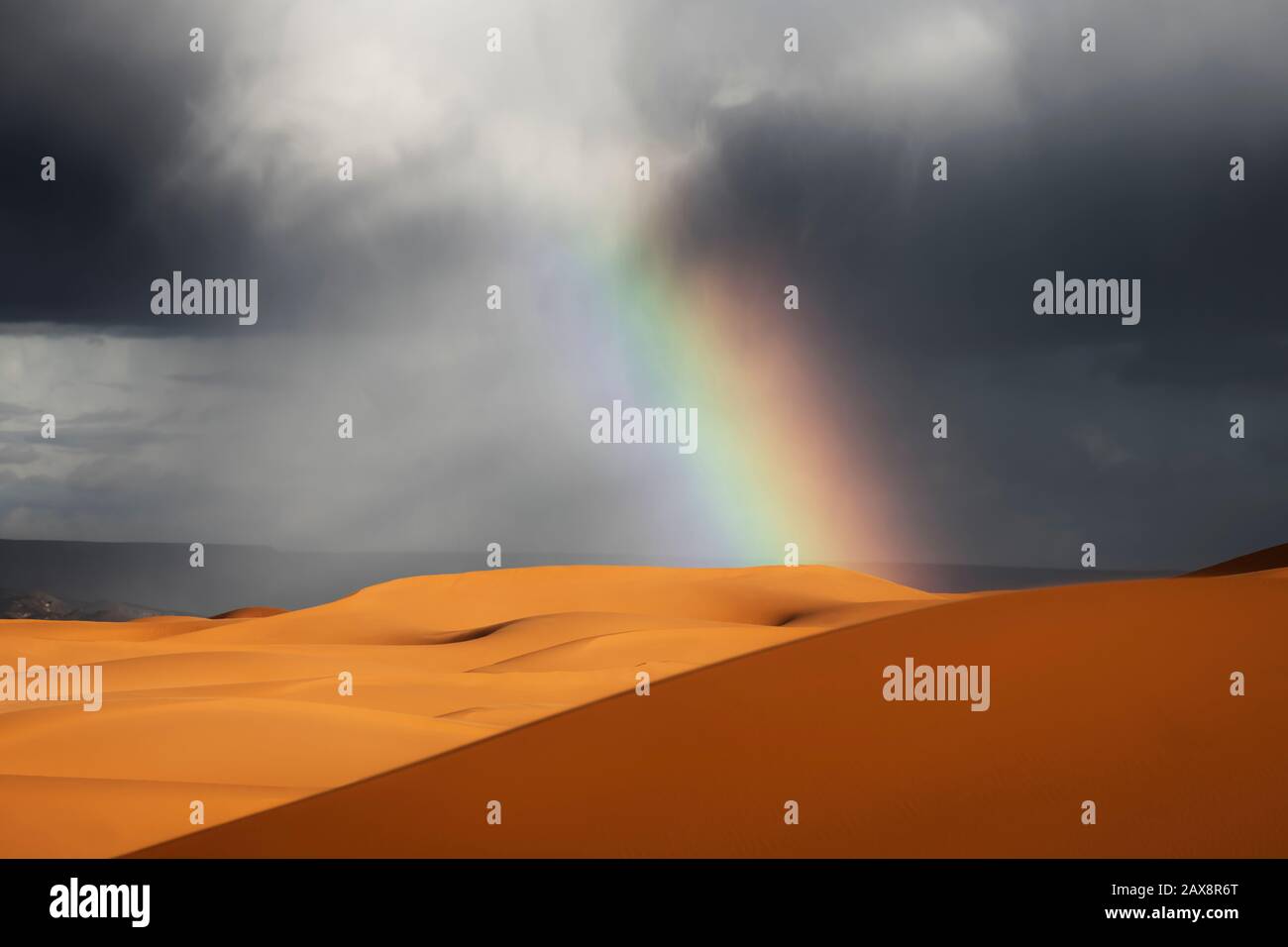 Sahara desert sand dunes with rainbow against dark, cloudy, rainy sky ...