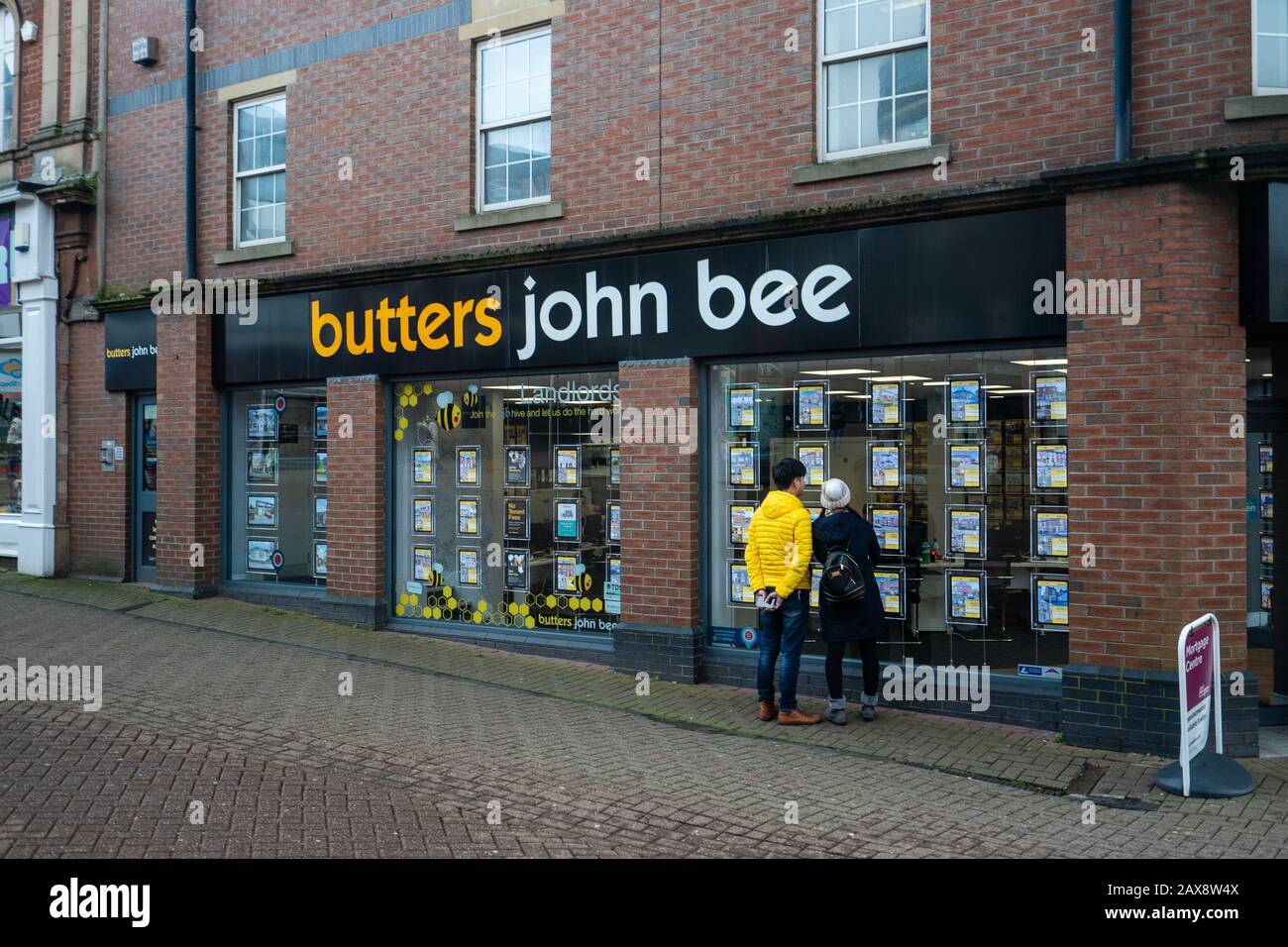 A couple browse properties in the window of Butters John Bee Estate ...