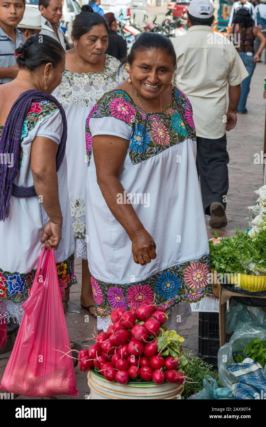 Woman selling vegetables, wearing huipil, traditional hand-embroided Mayan dress, at Calle 44 in ...