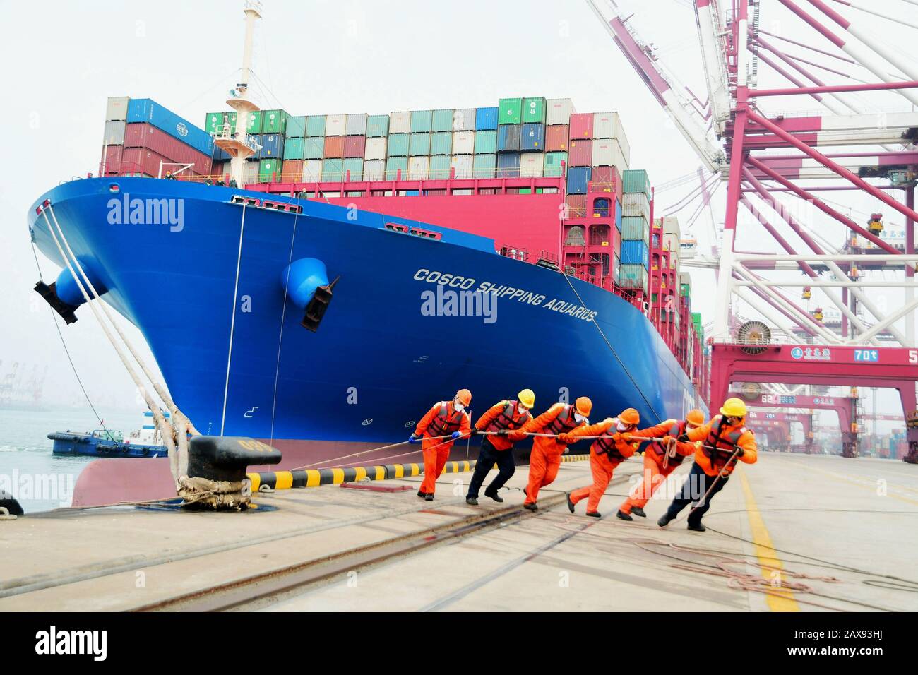 Port workers dock a container ship on a quay at the Port of Qingdao in ...