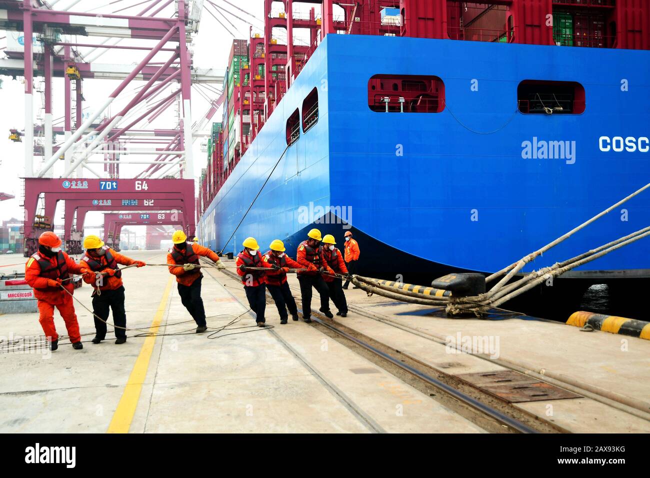 Port workers dock a container ship on a quay at the Port of Qingdao in ...