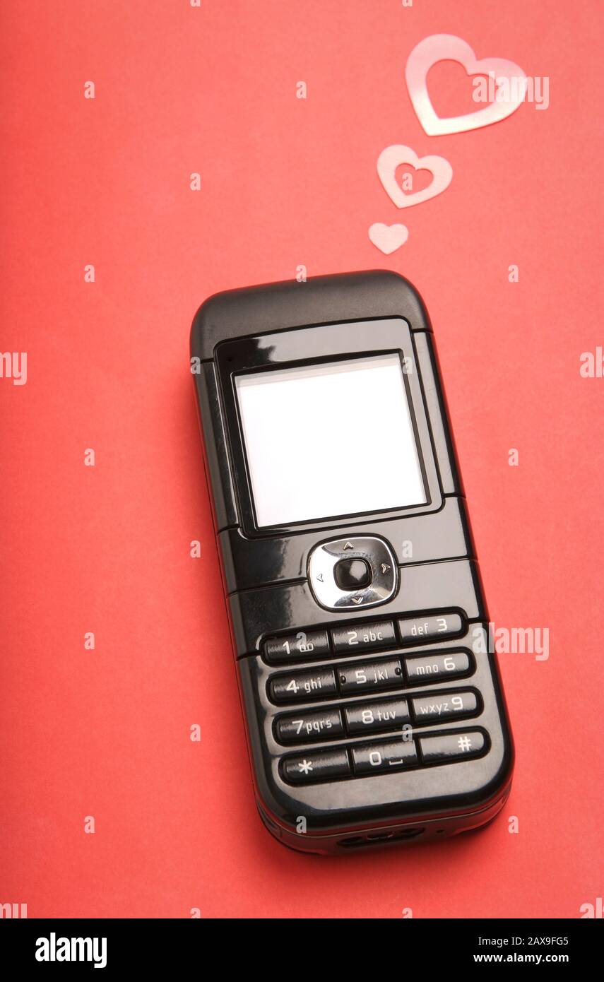 Old fashioned mobile phone on red background with three hearts sending ...