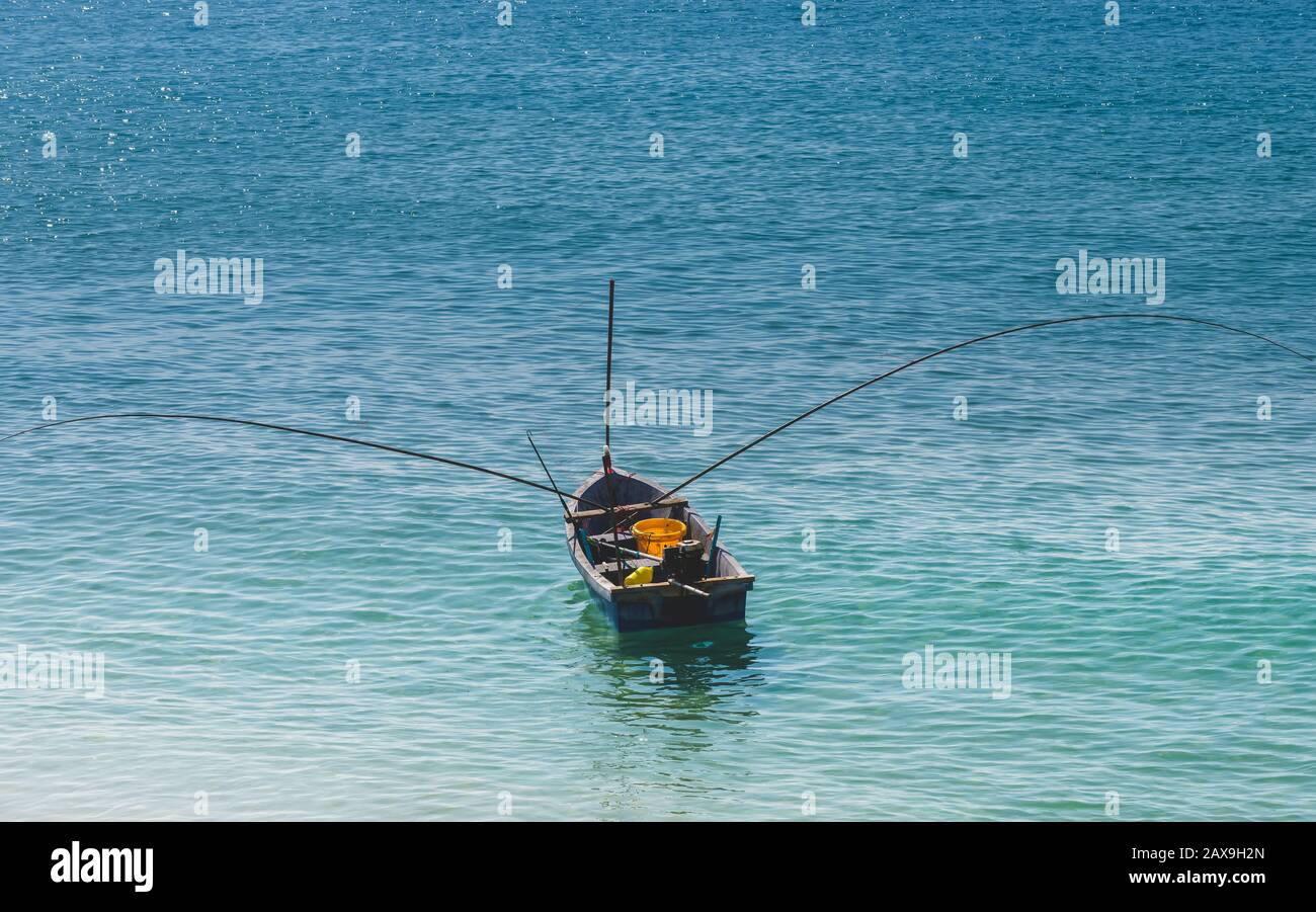 Small wooden fishing boat in the blue sea with outdoor sun lighting ...